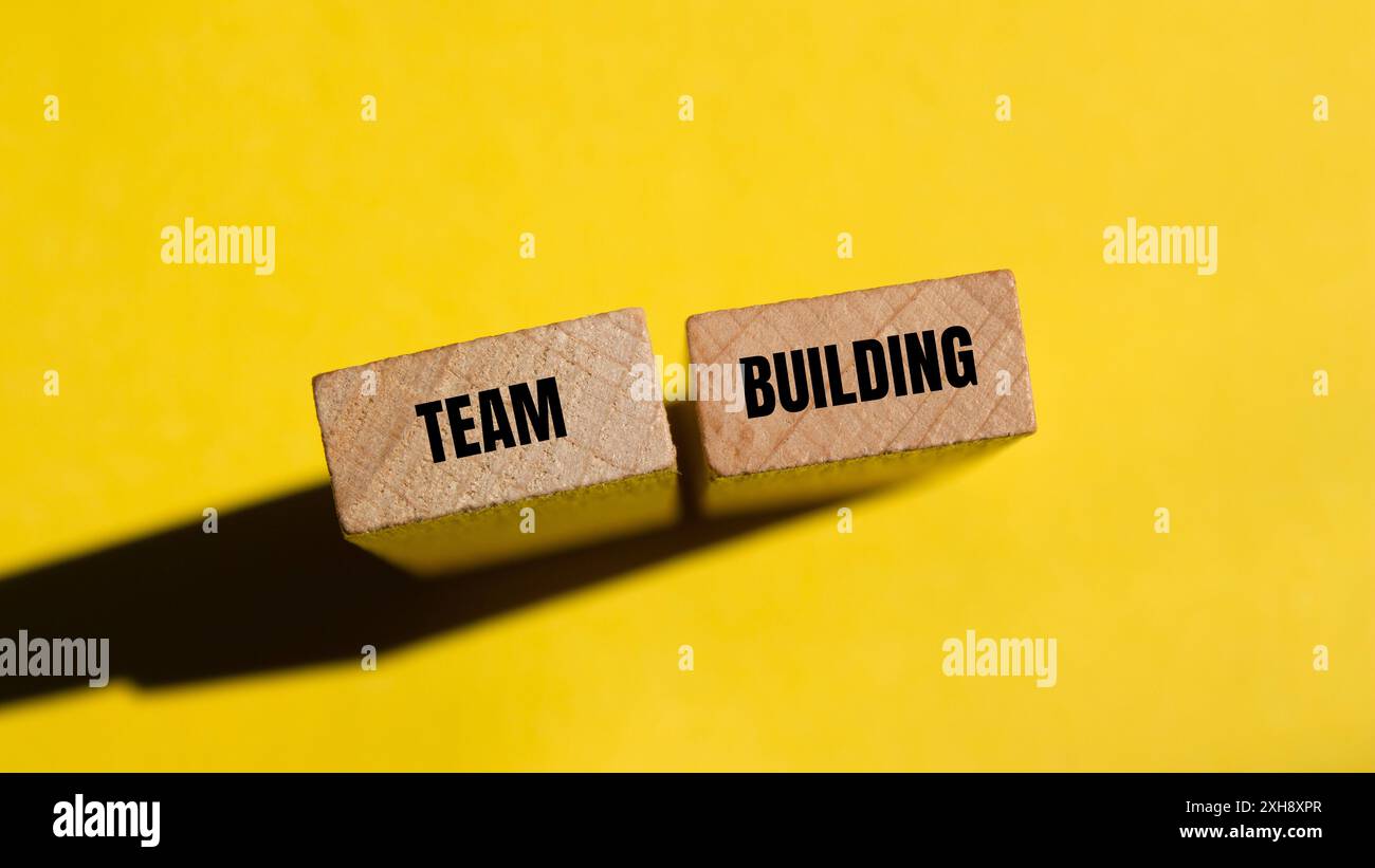 Team building message written on wooden blocks with yellow background ...