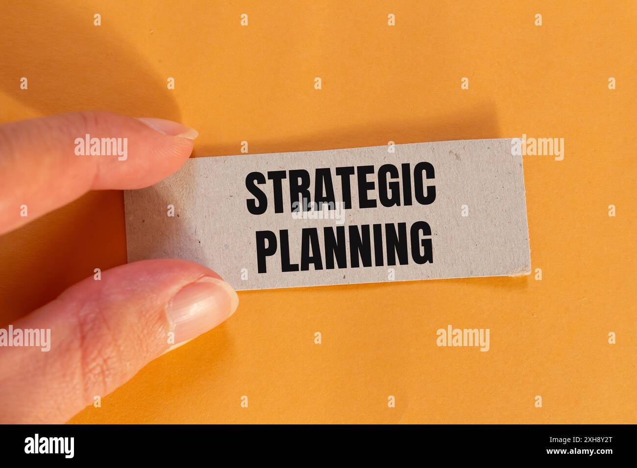 Strategic planning message written on ripped paper piece with orange ...