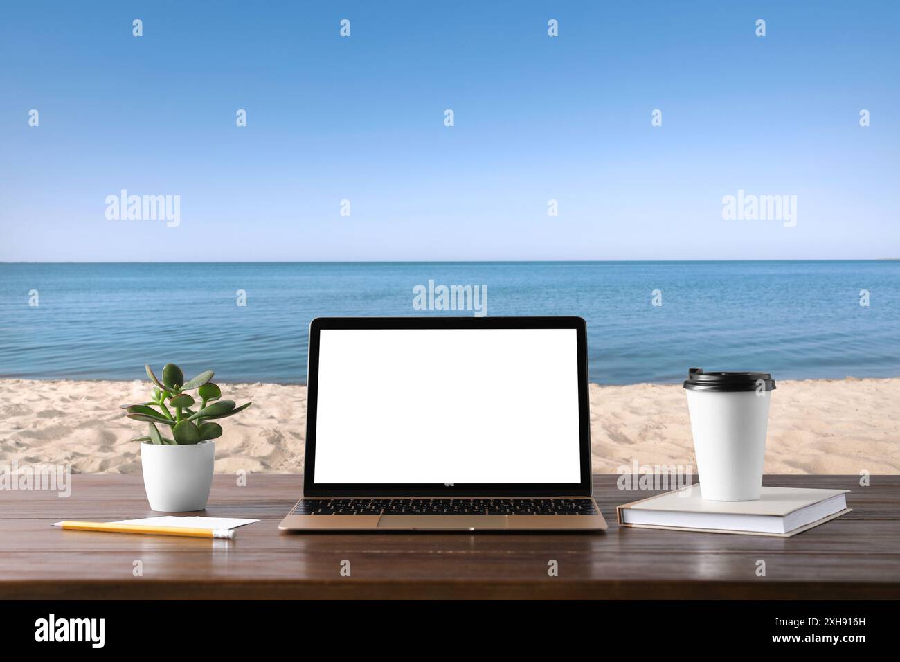 Workplace at beach, distant office. Table with laptop on sandy seashore ...