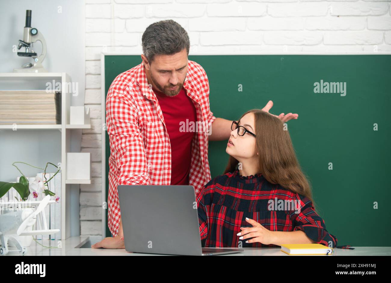 Teacher helping school kids in classroom at school Stock Photo - Alamy