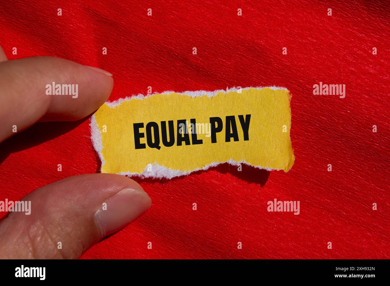 Equal pay message written on ripped yellow paper with red background ...
