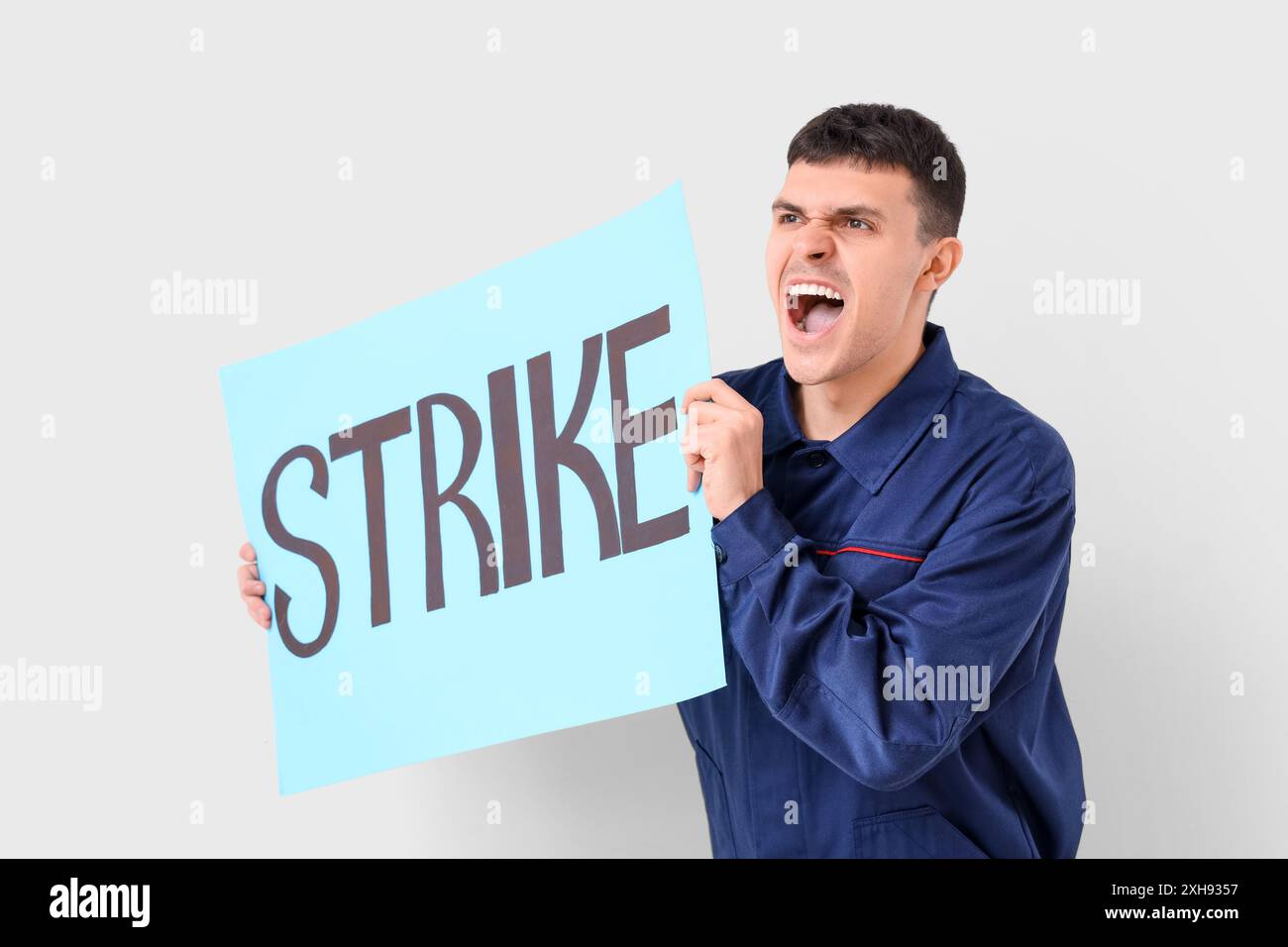 Protesting mechanic holding placard with word STRIKE on light ...