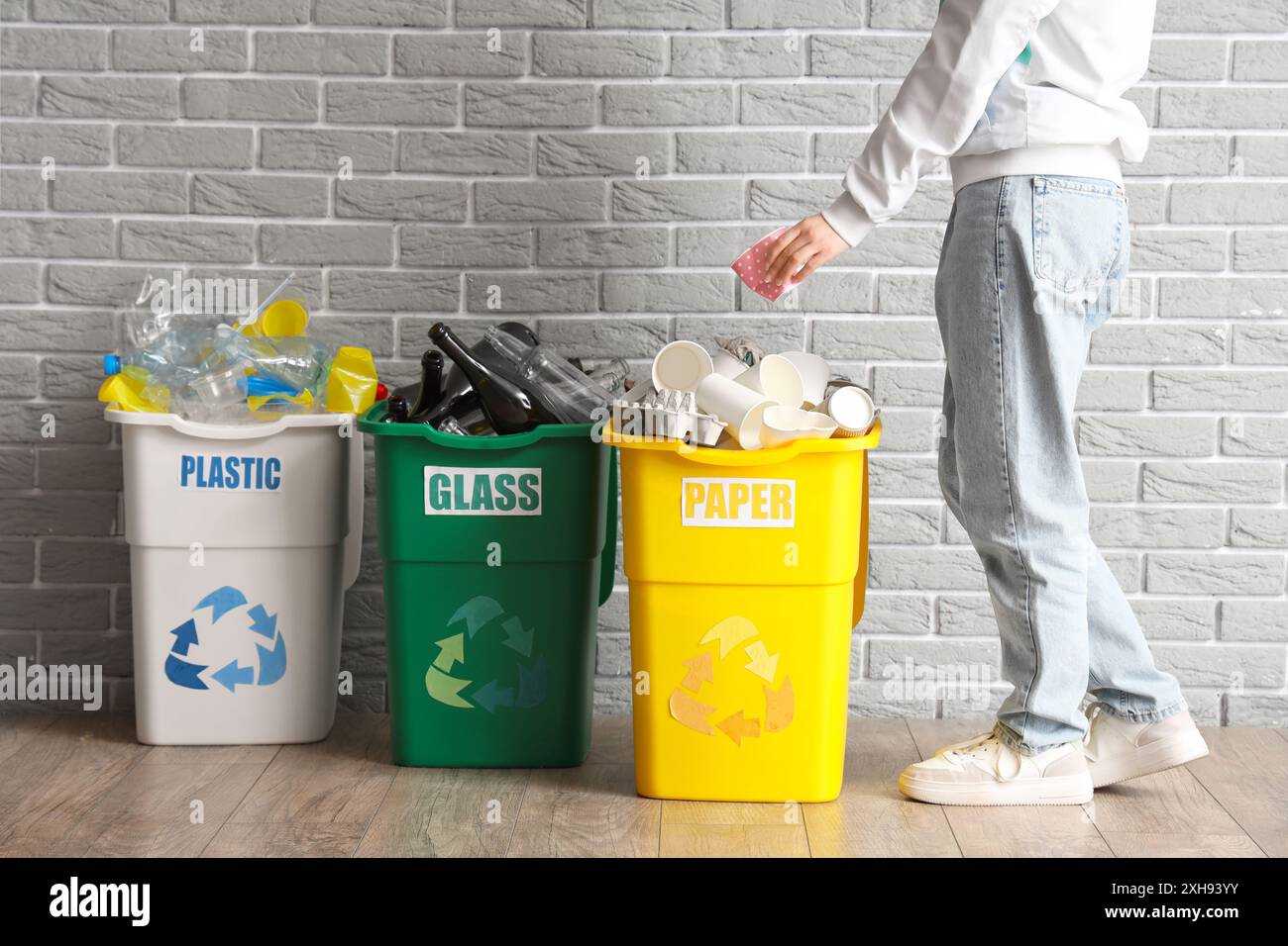 Woman putting garbage into full trash bins with different types of ...
