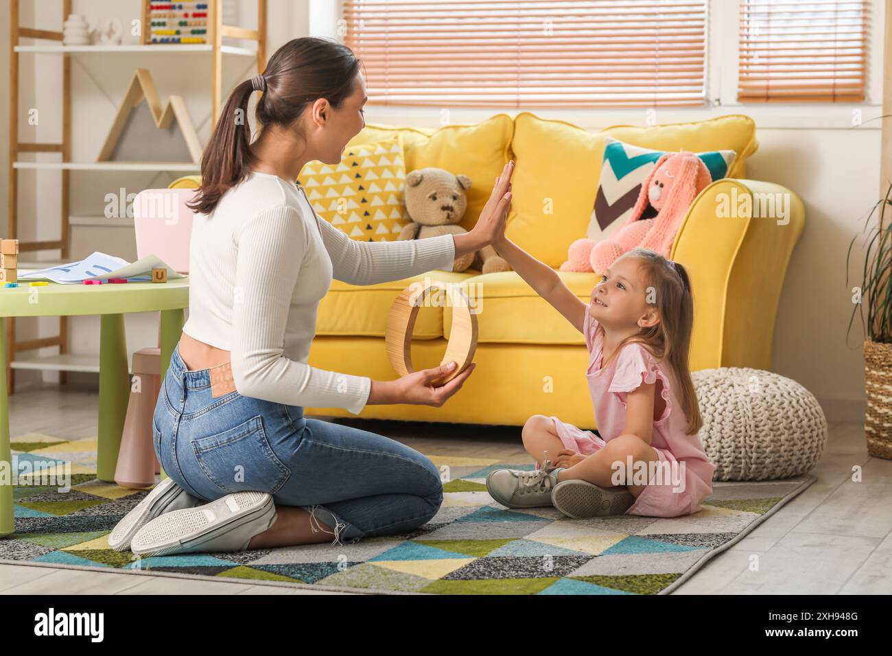 Female speech therapist with cute little girl giving each other high ...