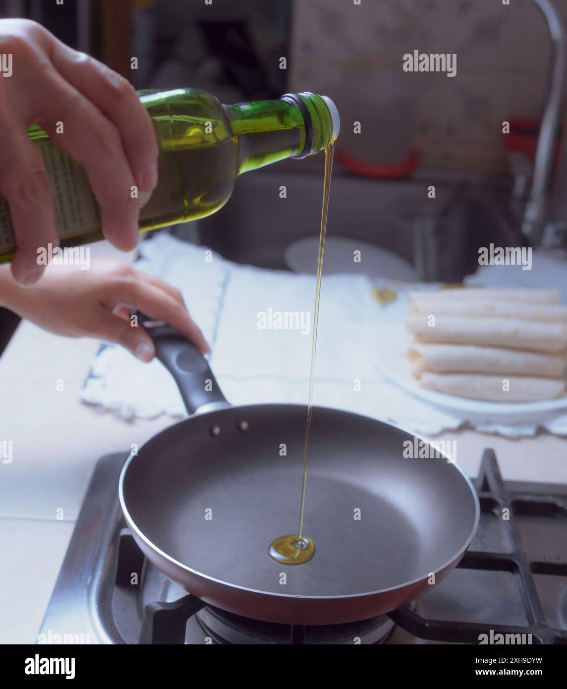 Pouring oil into the hot frying pan, inside a Mexican kitchen, only ...