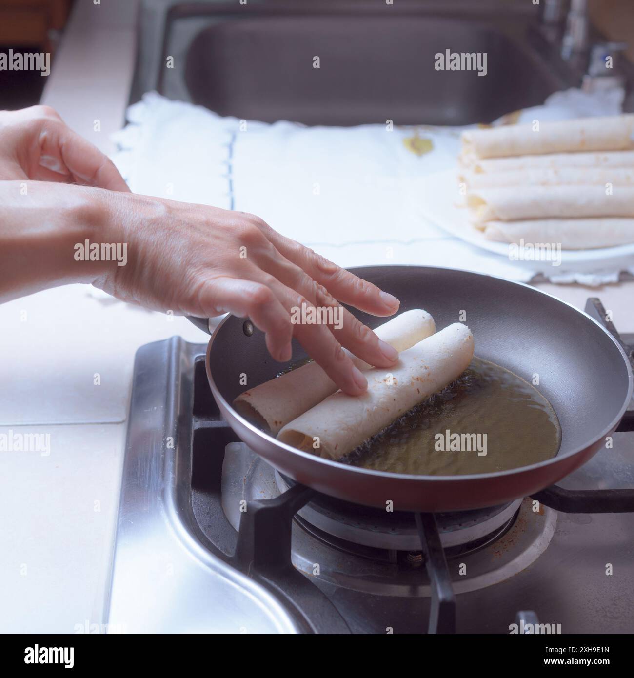 Preparation of fried tacos in a frying pan, you can only see some hands ...