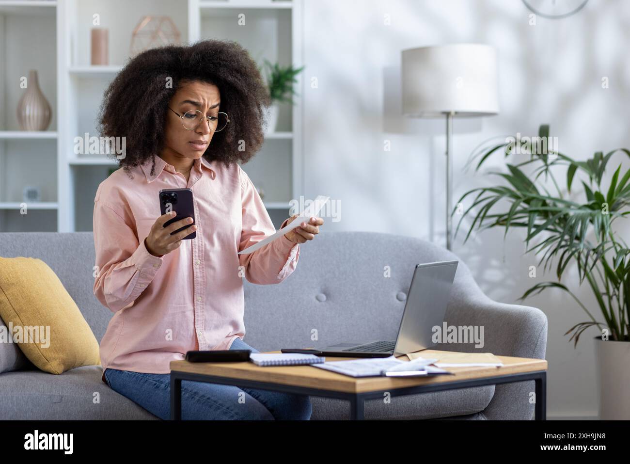 Woman checking receipt while using smartphone and laptop in modern ...