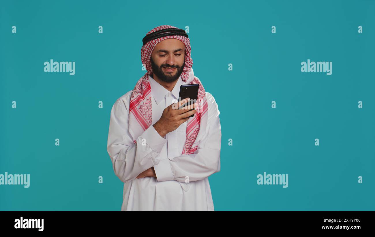 Muslim man in traditional clothing using smartphone, engaged in online ...