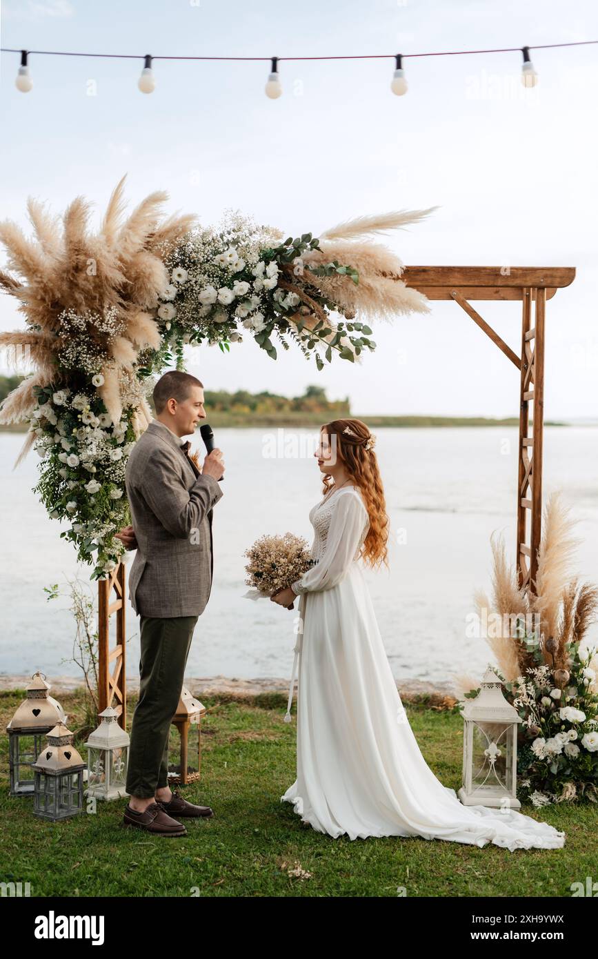 wedding ceremony of the newlyweds in a country cottage on a green hill ...