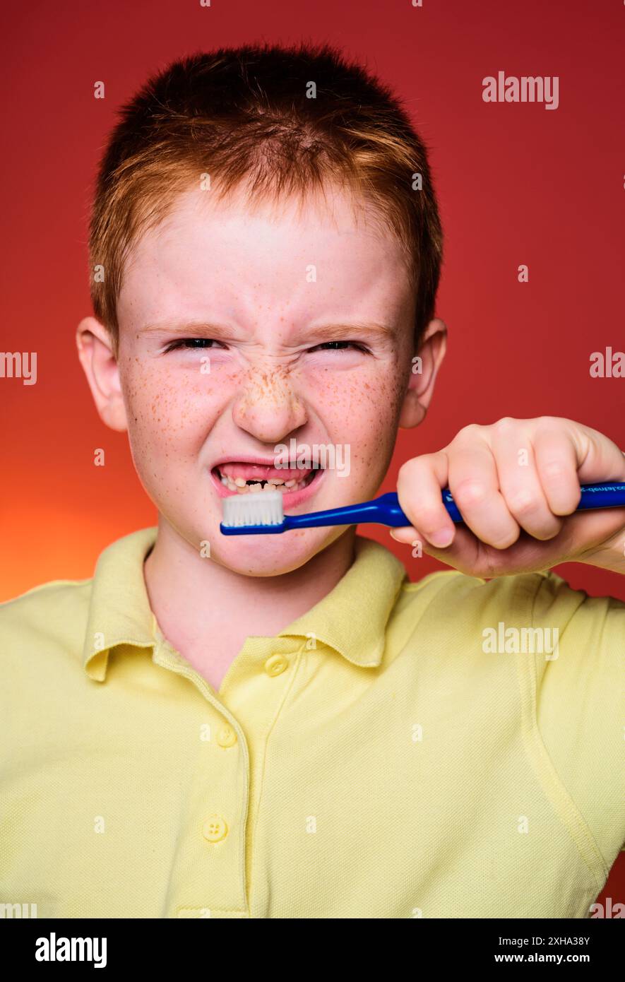 Red-haired boy with funny face is brushing teeth with toothbrush ...