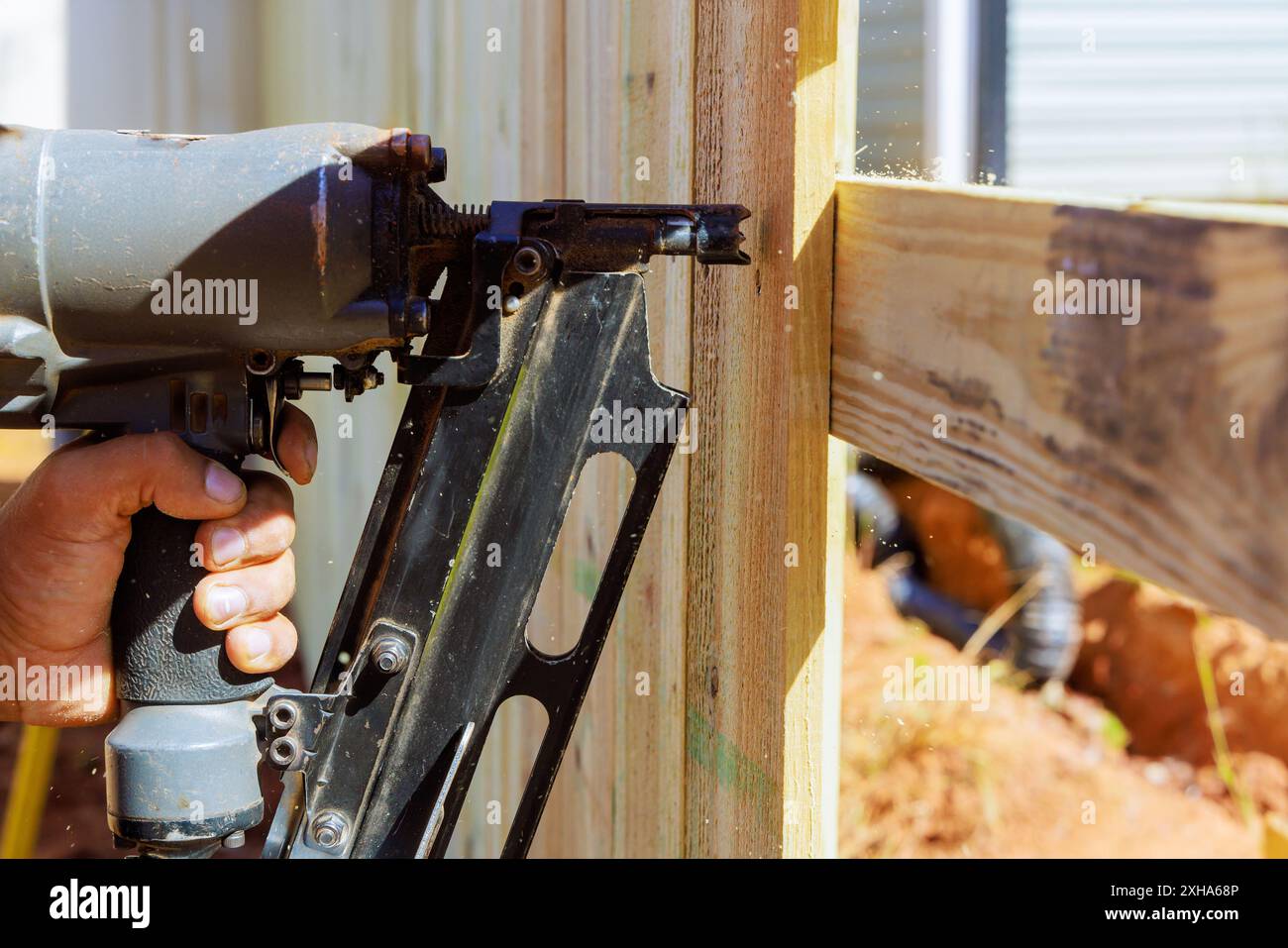 Worker nailing wooden fence during work using air pneumatic gun Stock ...