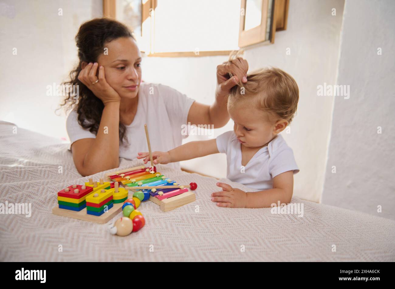 Mother interacting with her baby who is playing with vibrant wooden ...