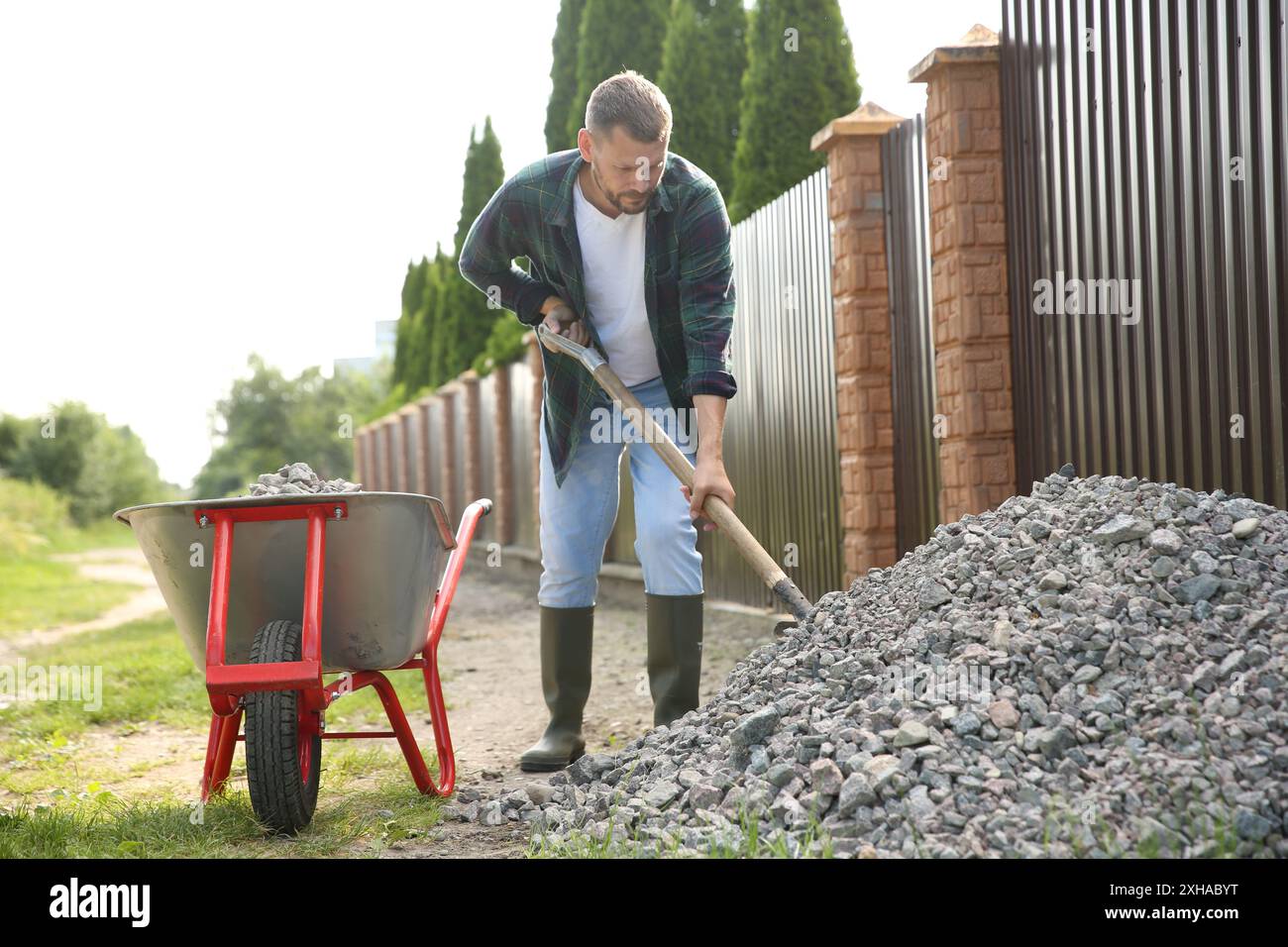 Man picking stones up with shovel and wheelbarrow outdoors Stock Photo ...