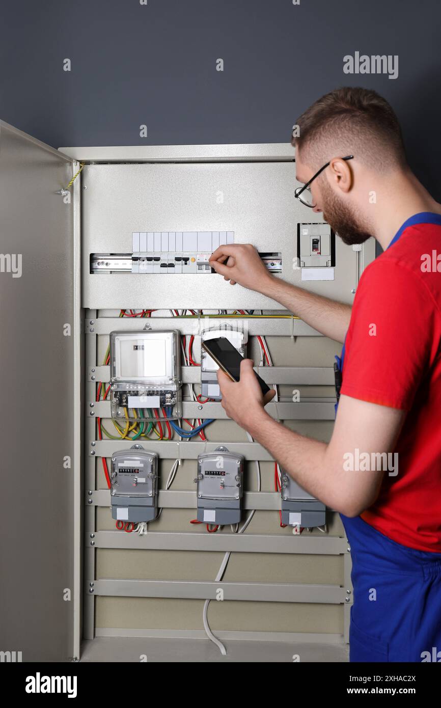 Technician worker with smartphone inspecting electricity meter Stock ...