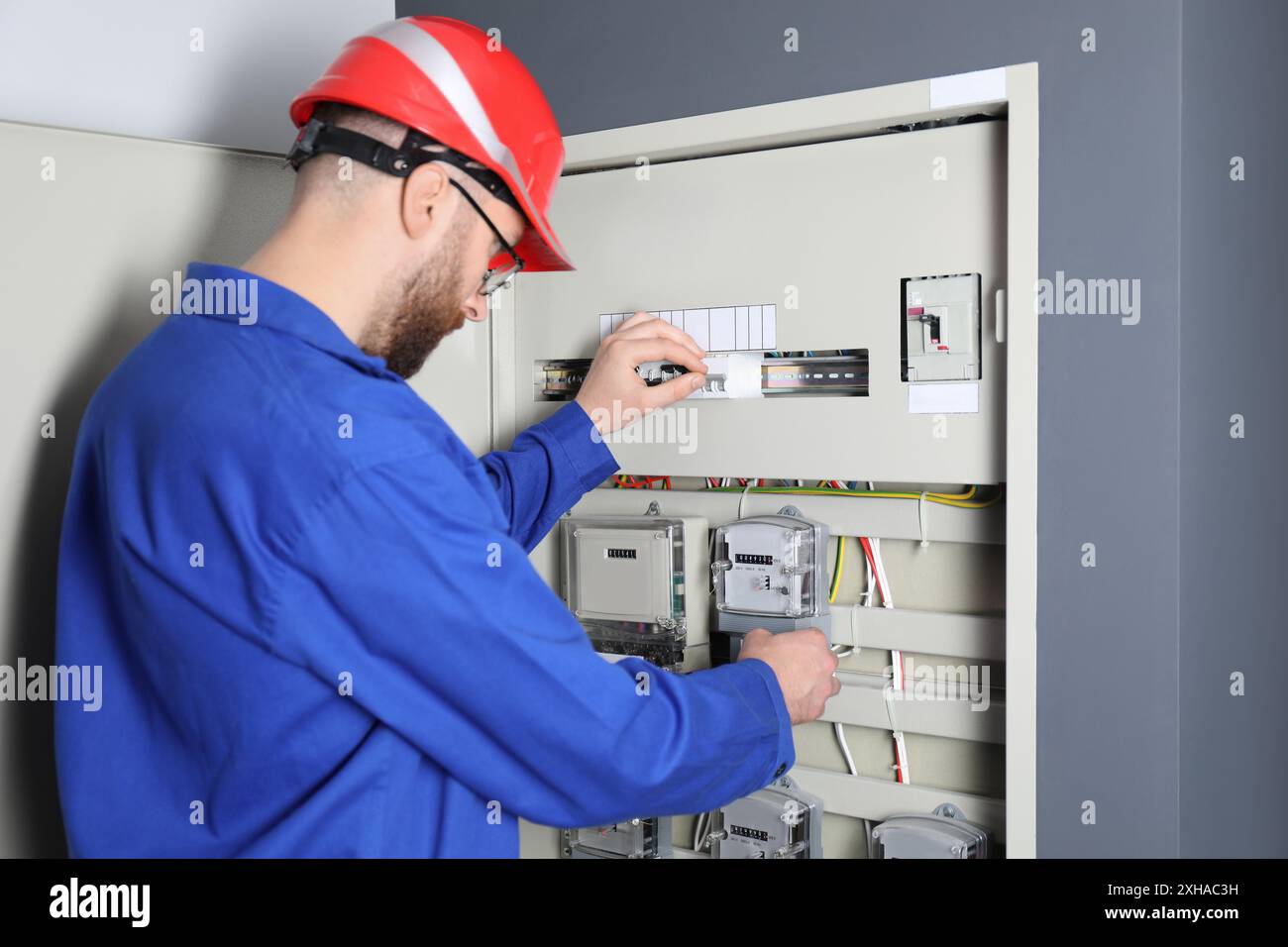 Electrician wearing uniform installing electricity meter indoors Stock ...