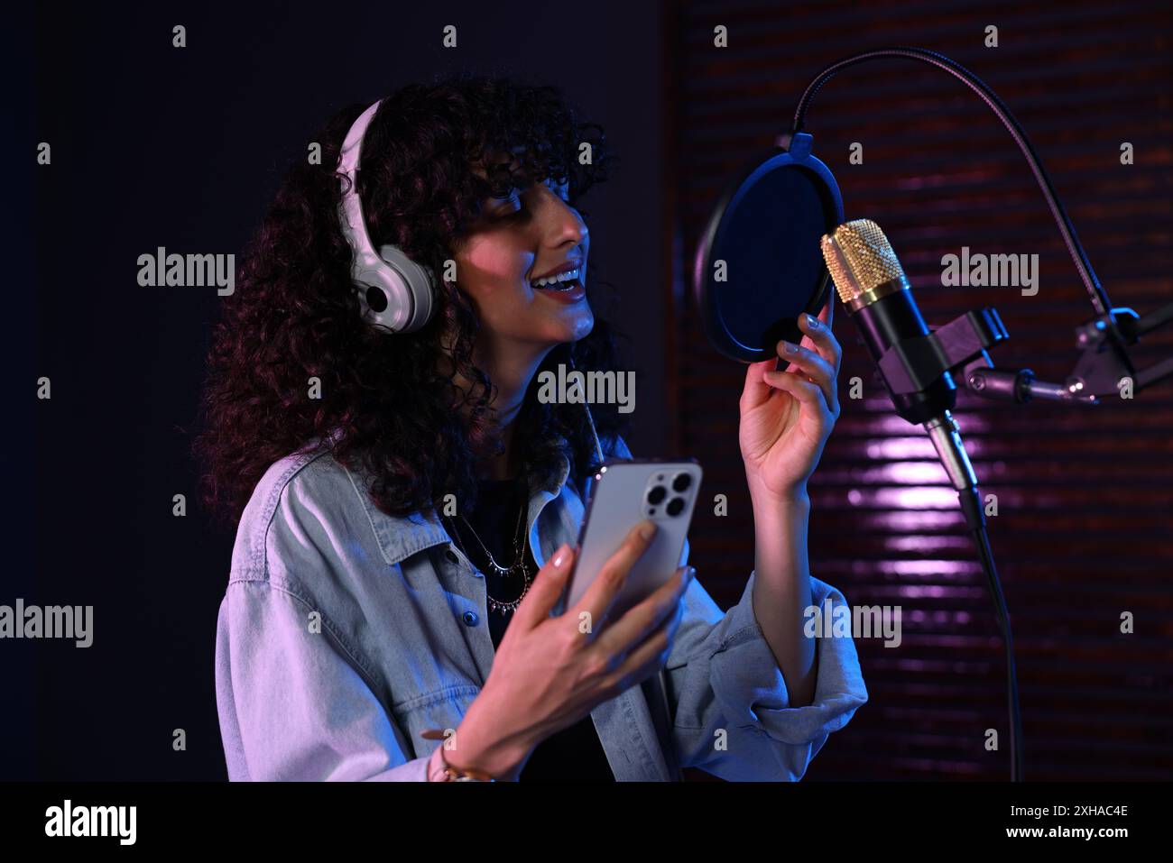 Vocalist with smartphone singing into microphone in professional record ...