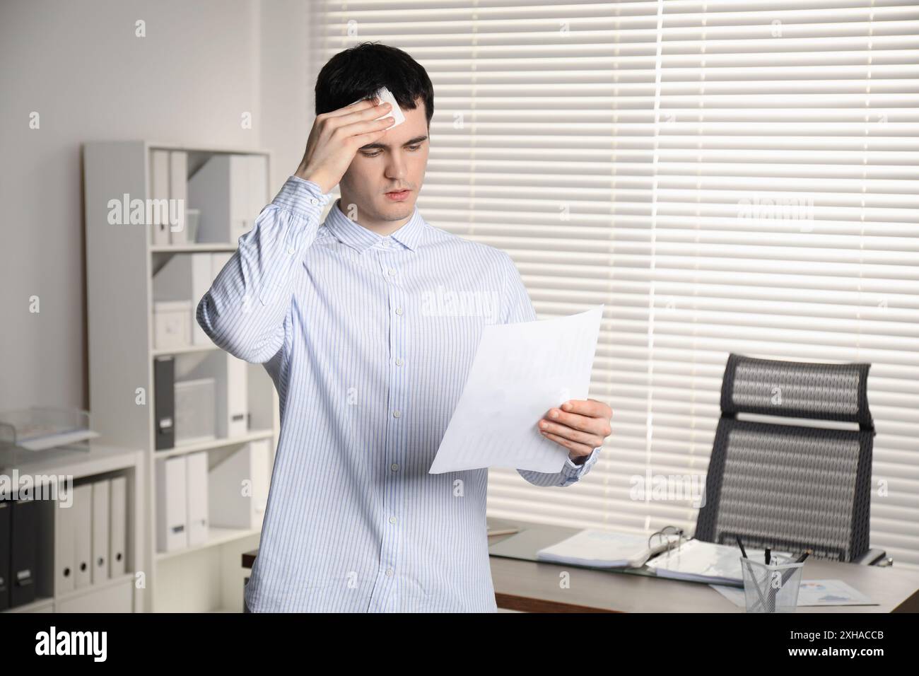 Embarrassed man with tissue and document in office Stock Photo - Alamy
