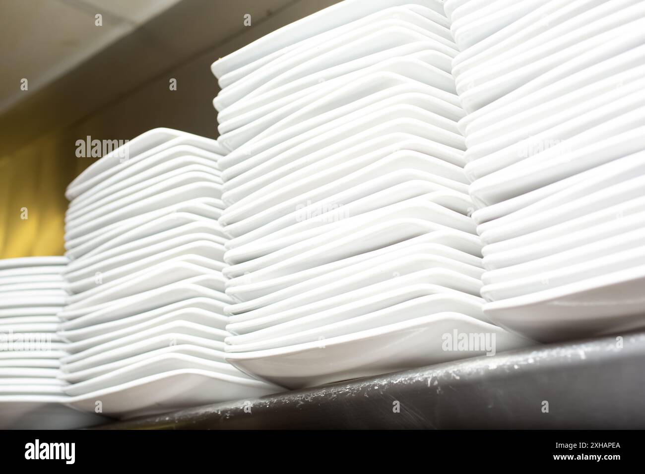 A view of stacks of plates on a shelf, in a restaurant kitchen setting ...