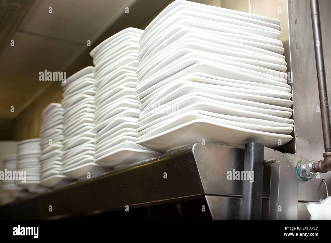 A view of several stacks of white plates on a shelf, in a restaurant ...