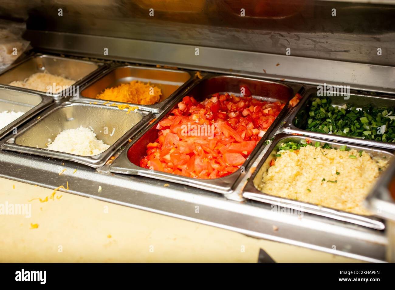 A view of several ingredient bins on a counter surface, in a restaurant ...