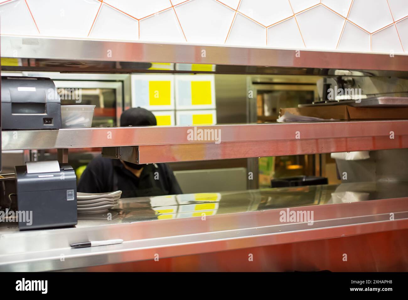 A view of the cooks prepping entrees behind a restaurant pass-thru ...