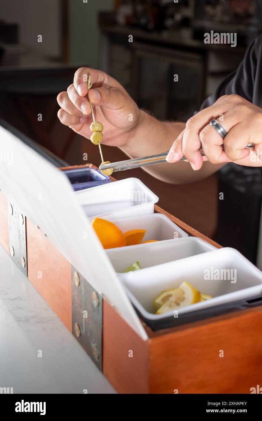 A view of a bartender preparing fruit and vegetable garnishes, in a bar ...