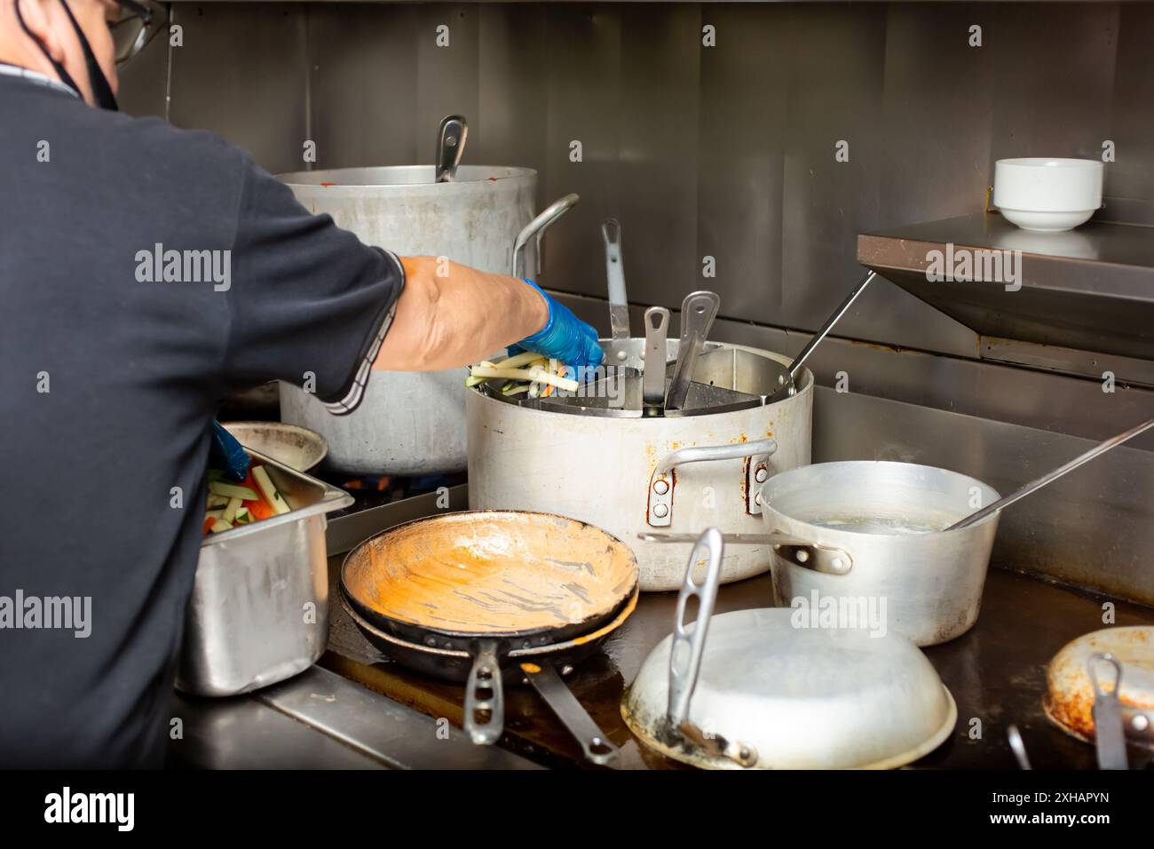 A view of a line cook managing food prep in a busy restaurant kitchen ...