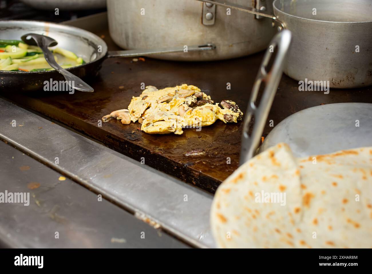 A view of an egg scramble cooking on a griddle, in a restaurant kitchen ...