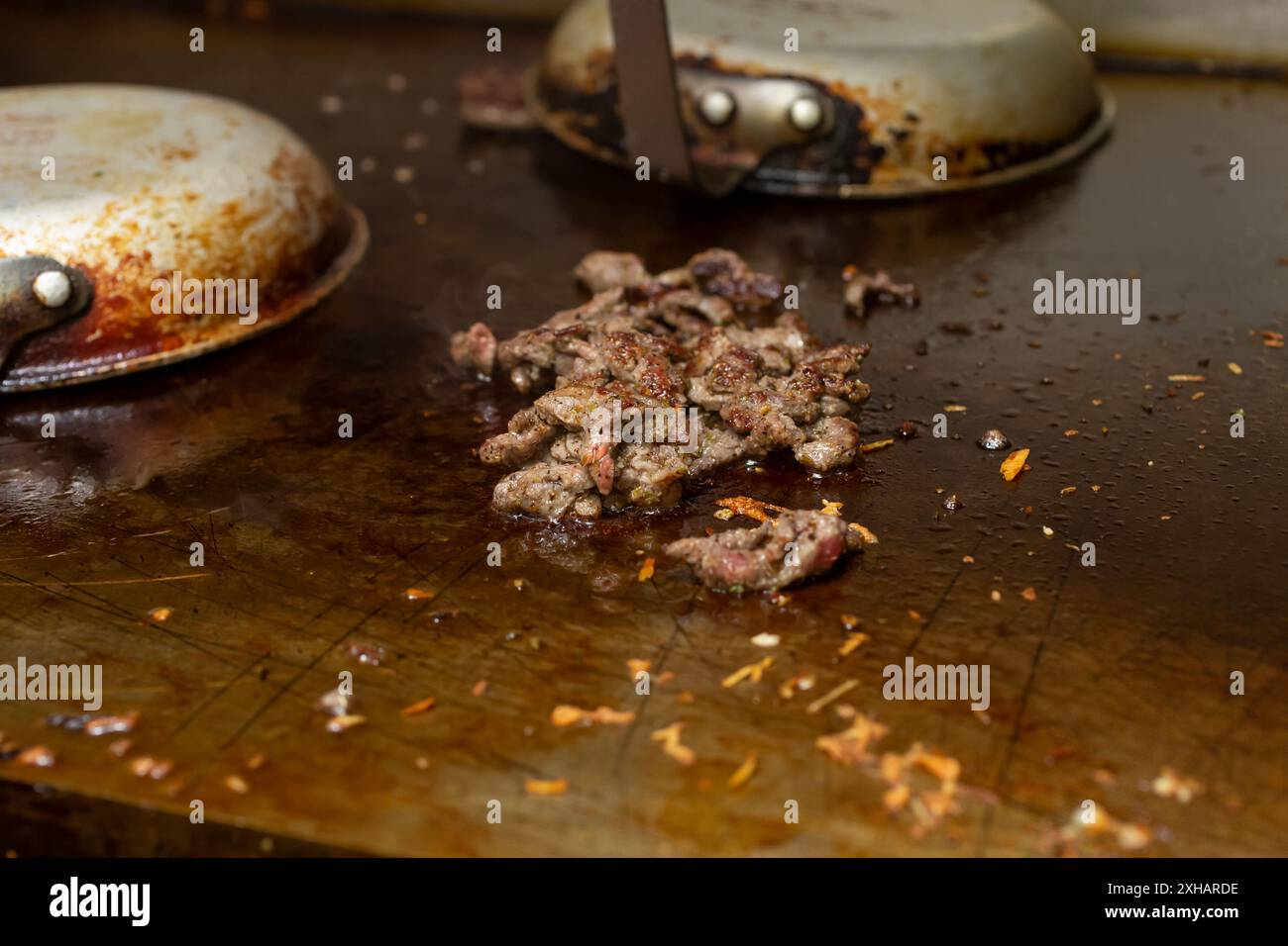A view of chopped beef cooking on a griddle, in a restaurant kitchen ...