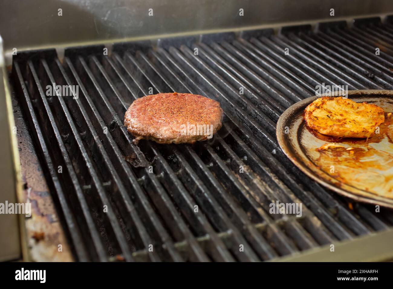 A view of a burger patty cooking on a grill, in a restaurant kitchen ...