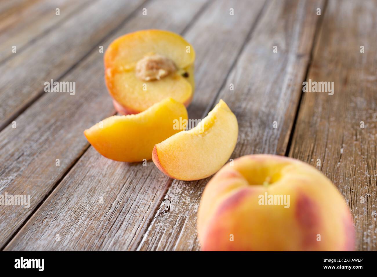 A view of peach parts scattered around a wood table surface Stock Photo ...
