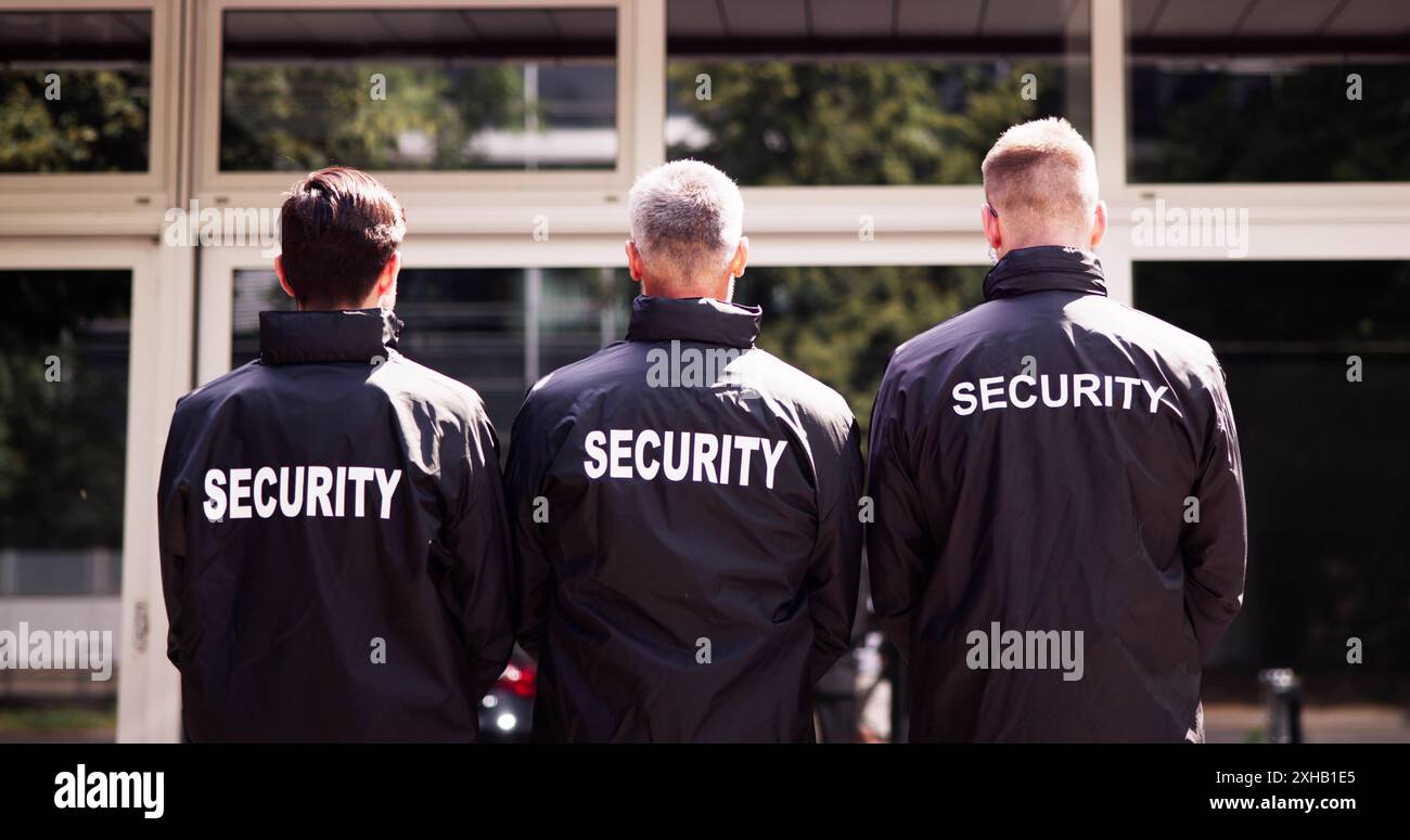 Security team of uniformed guards stand with hands clasped behind their ...