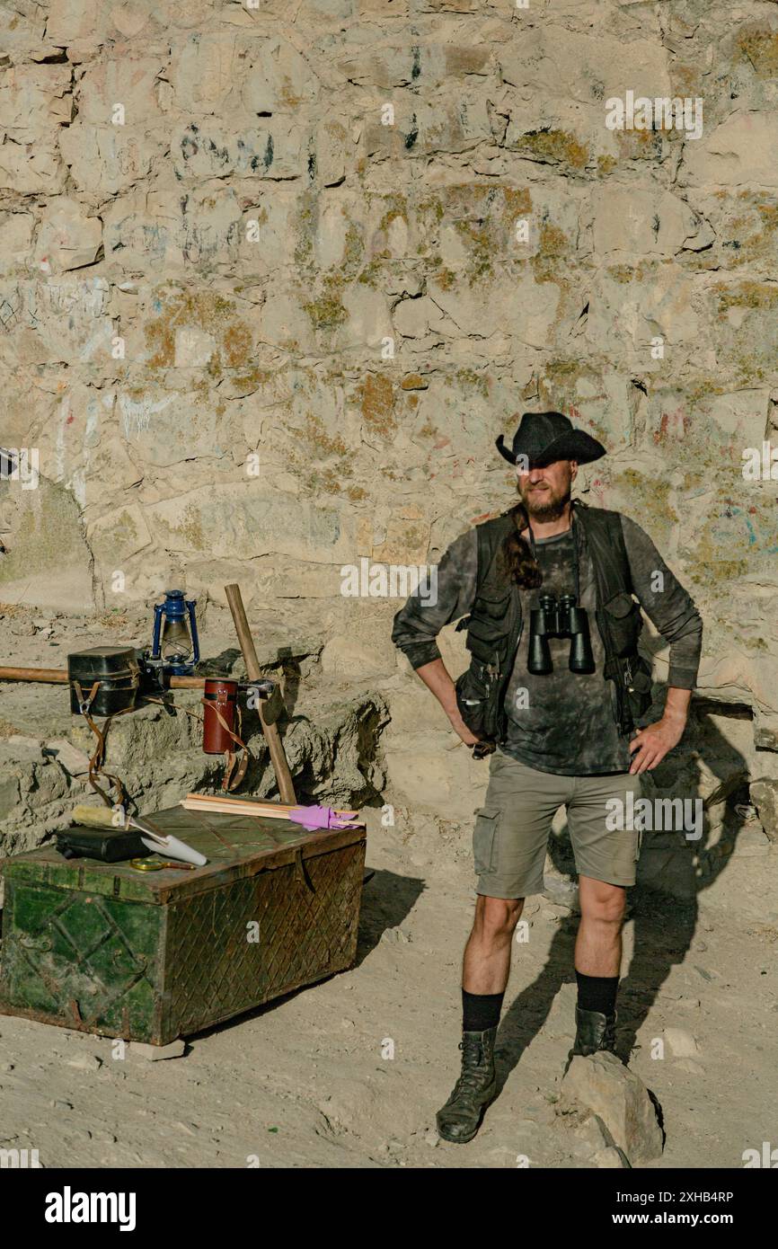 An archaeologist with his equipment near a chest against the backdrop ...