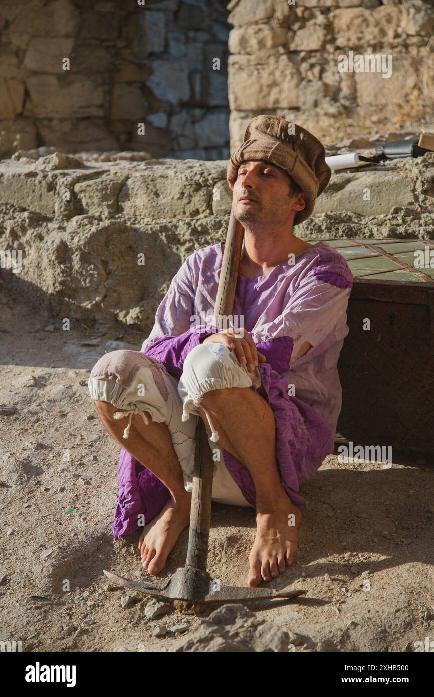 A mercenary of Arab appearance sleeps sitting next to a chest with his ...