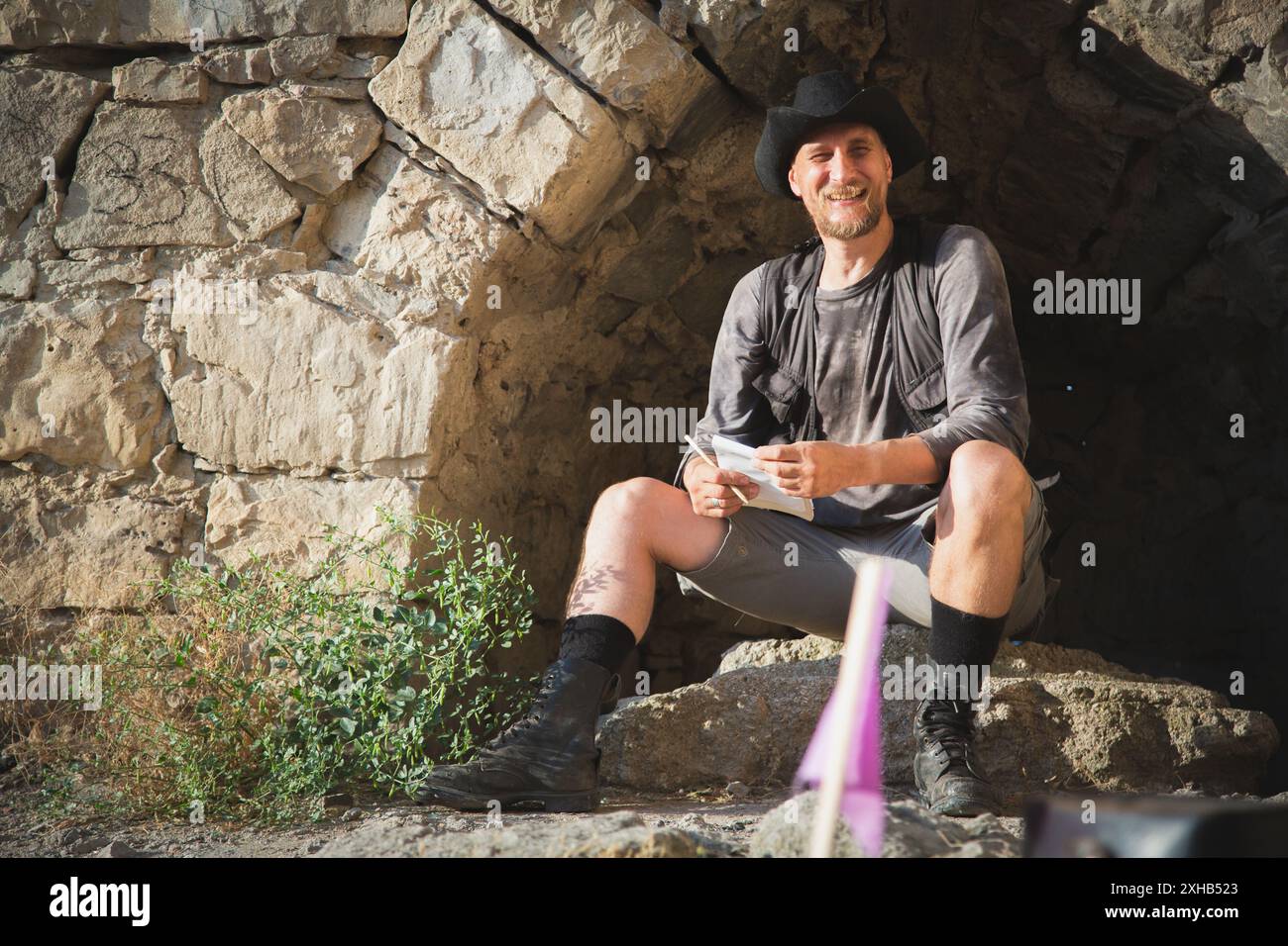 Happy Archaeologist in a funny hat works with notes against the ...