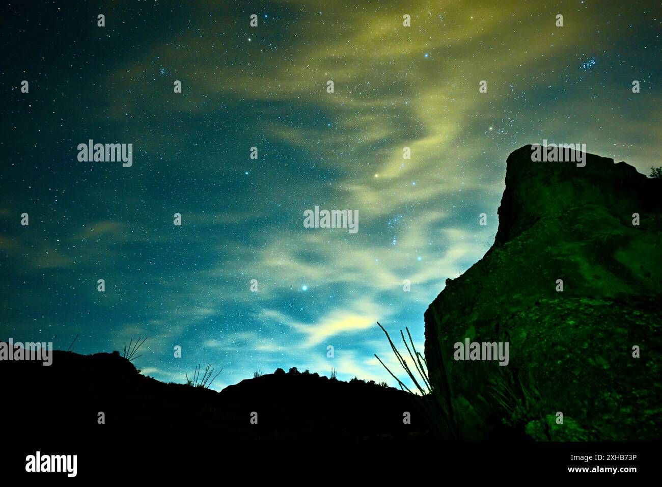 A starry night sky with clouds over a rocky landscape in the Arizona ...