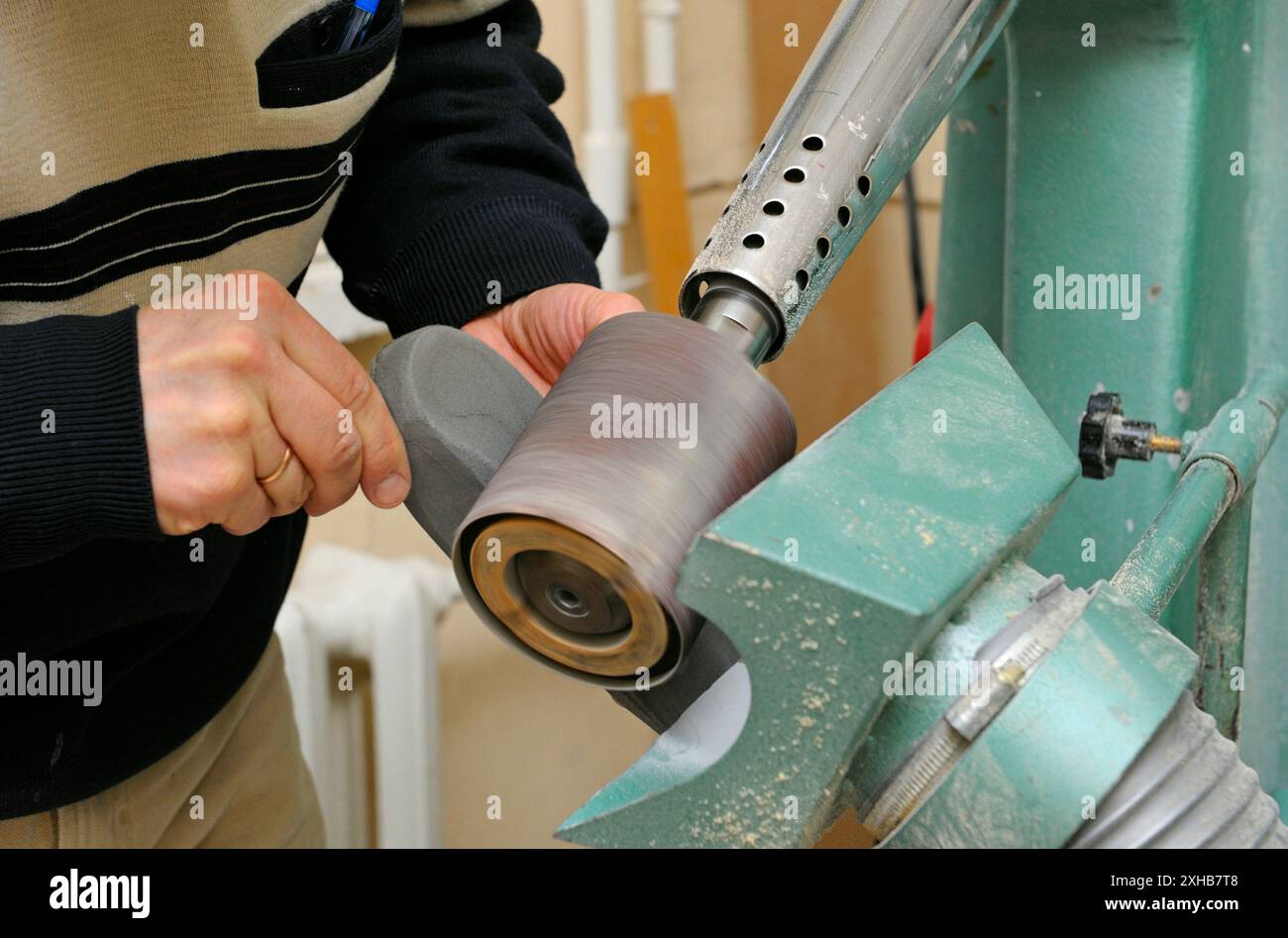 Worker sanding external prosthetic component using a belt grinding ...