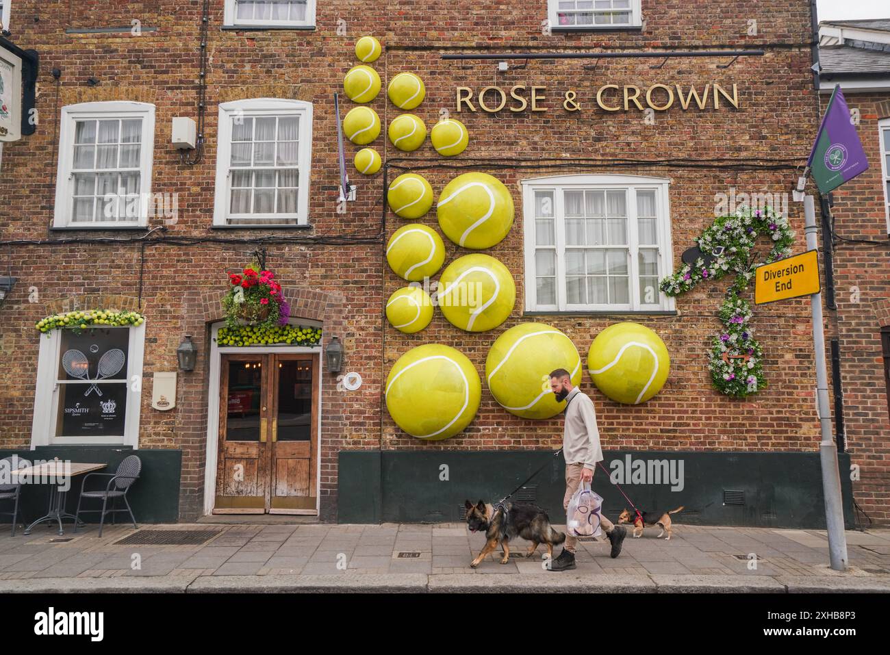 Wimbledon, London, UK. 13 July 2024 . A pedestrian walks past huge ...