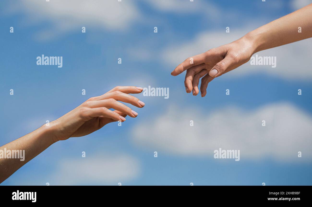 Two woman hands reaching towards each other on isolated sky background ...