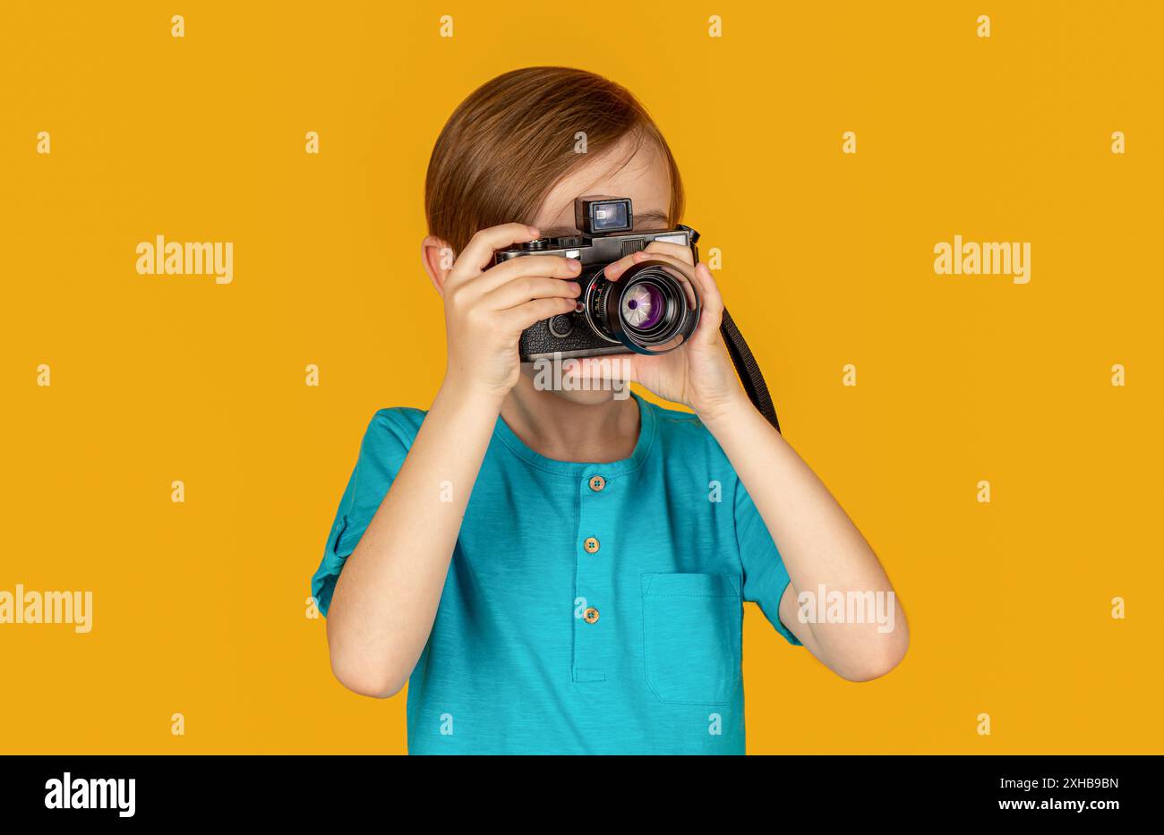 Boy with camera. Teen boy looks through a vintage camera and trying the ...