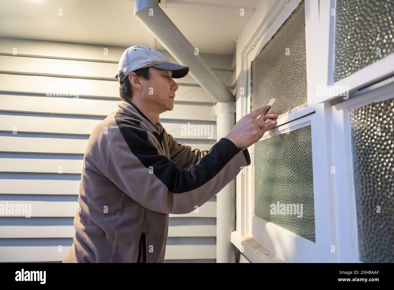 Worker applying window putty to a newly replaced glass. Home ...