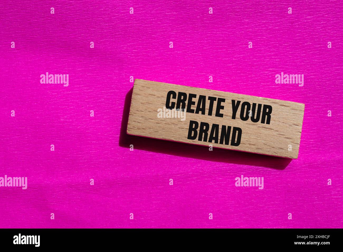 Create your brand words written on wooden block with pink background ...