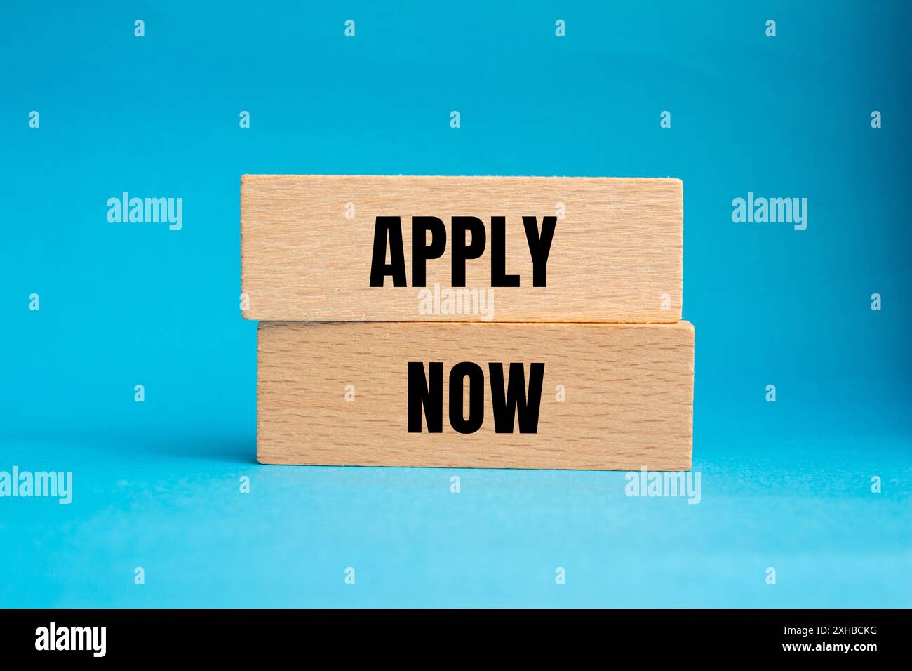 Apply now message written on wooden blocks with blue background. Conceptual apply now symbol ...
