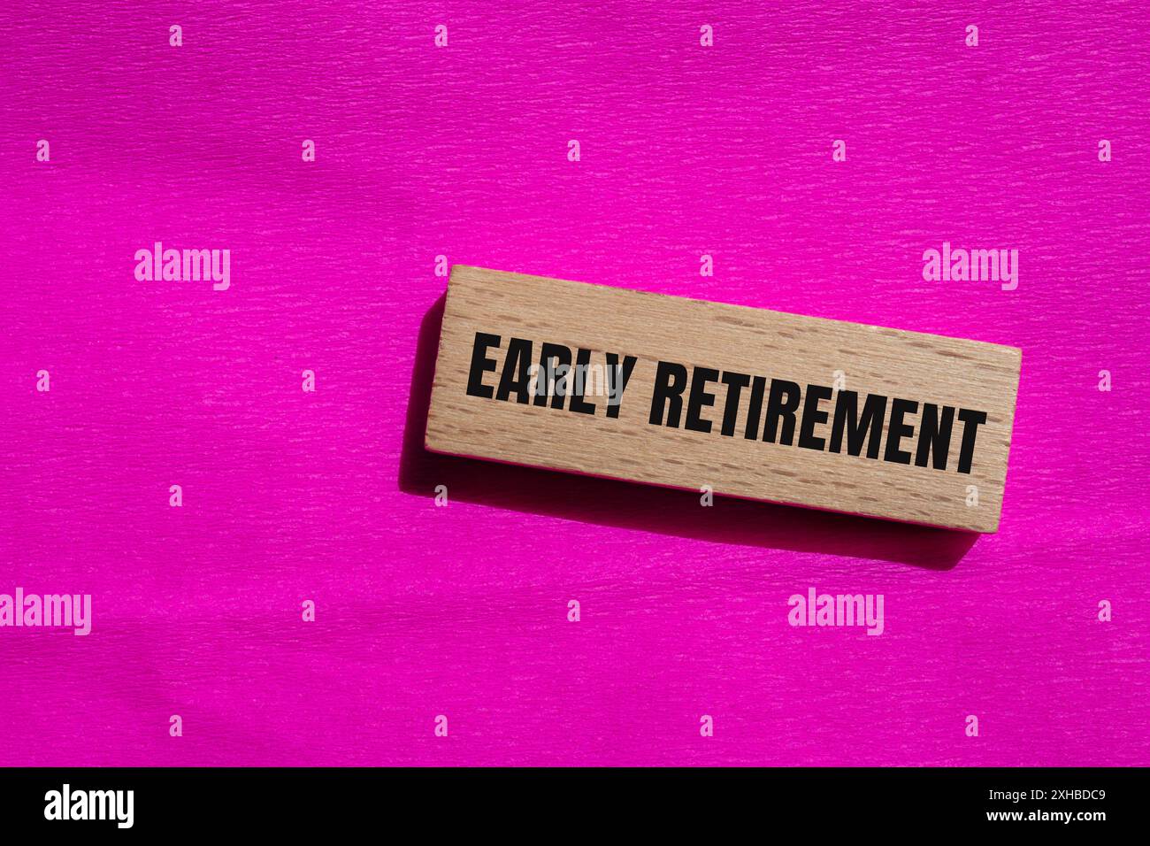 Early retirement words written on wooden block with pink background ...
