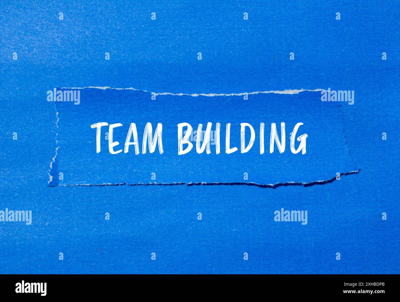 Team building message written on ripped paper piece with blue ...