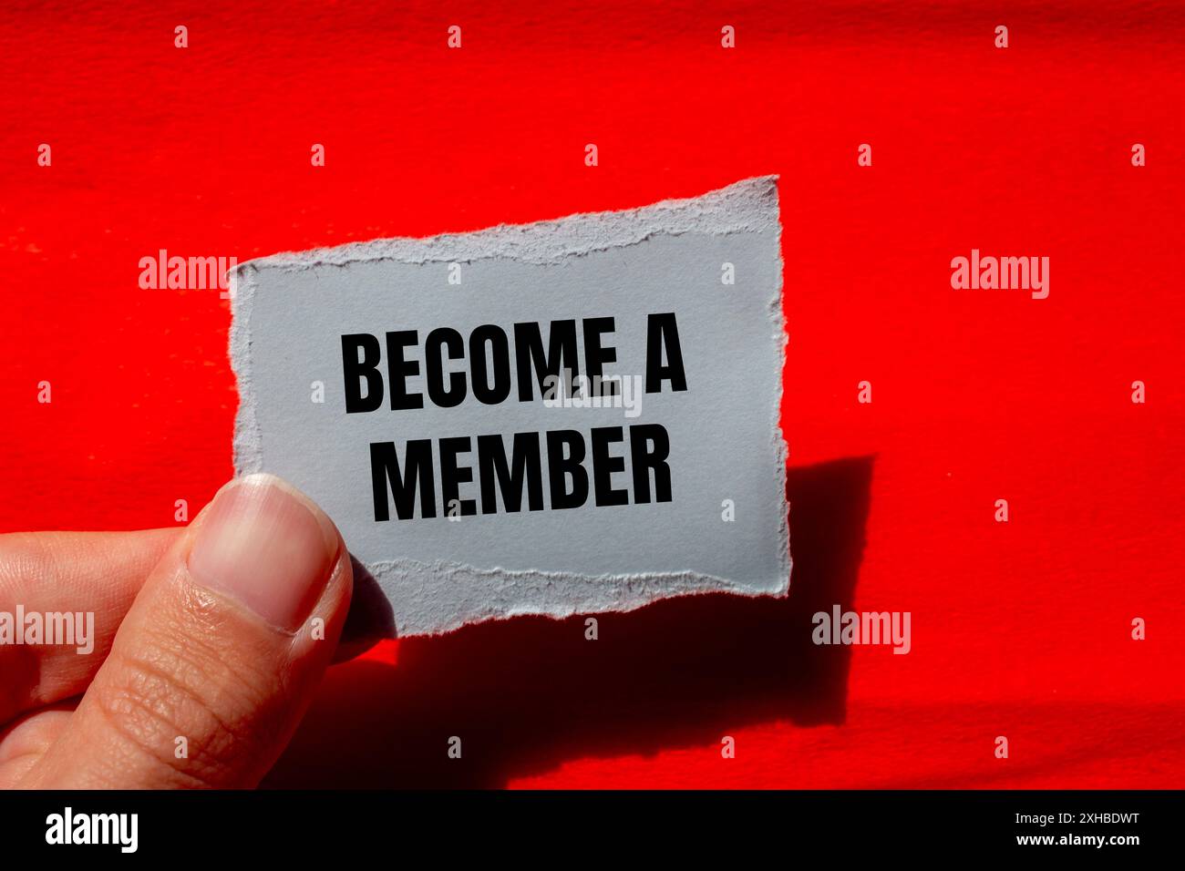 Become a member message written on ripped paper piece with red background. Conceptual become a ...