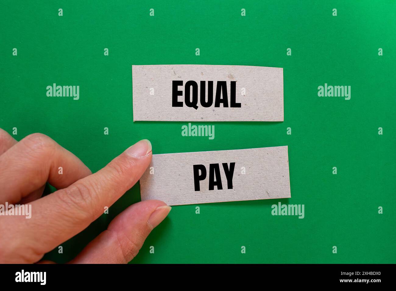 Equal pay message written on paper pieces with green background ...