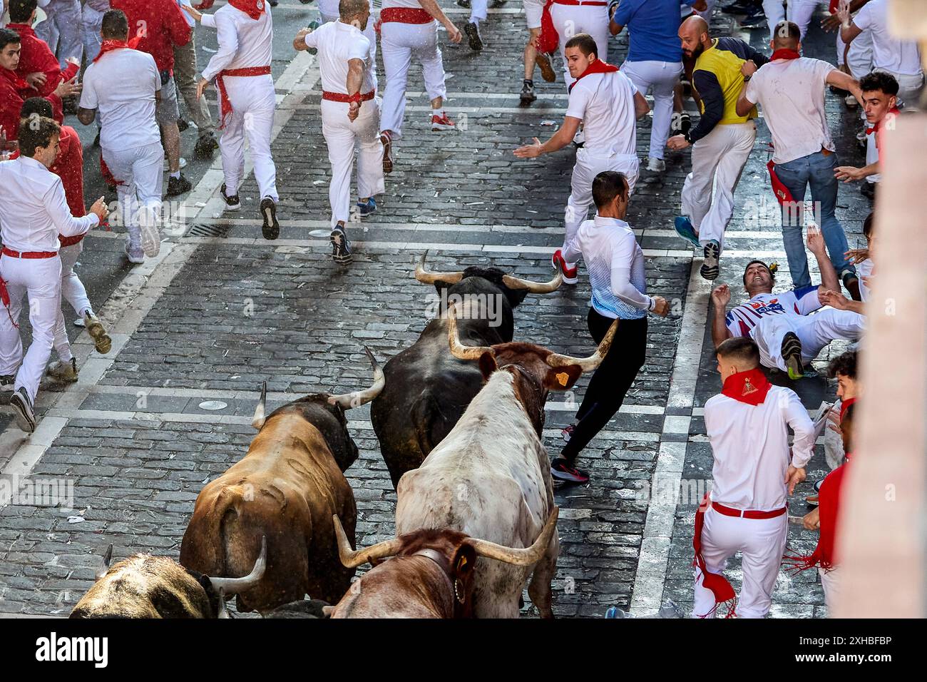 Several runners run in front of the bulls through the streets of ...