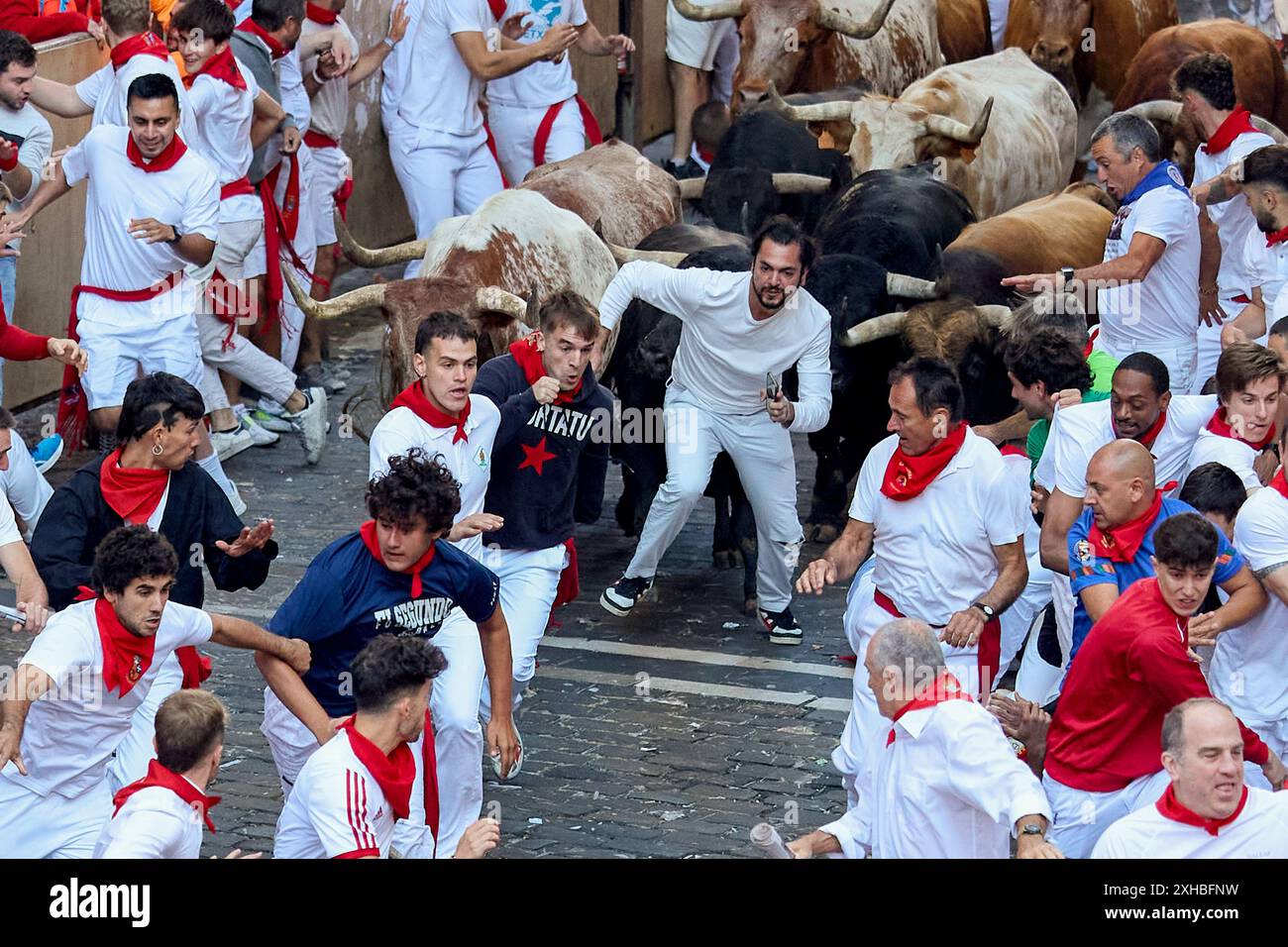 Several runners run in front of the bulls through the streets of ...