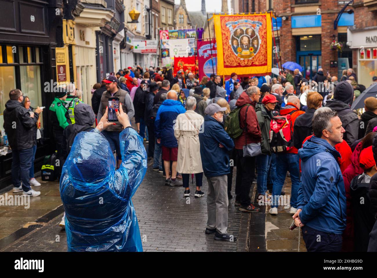 Durham, UK. 13 JUL, 2024. Lady in a poncho takes a photo as thousands ...